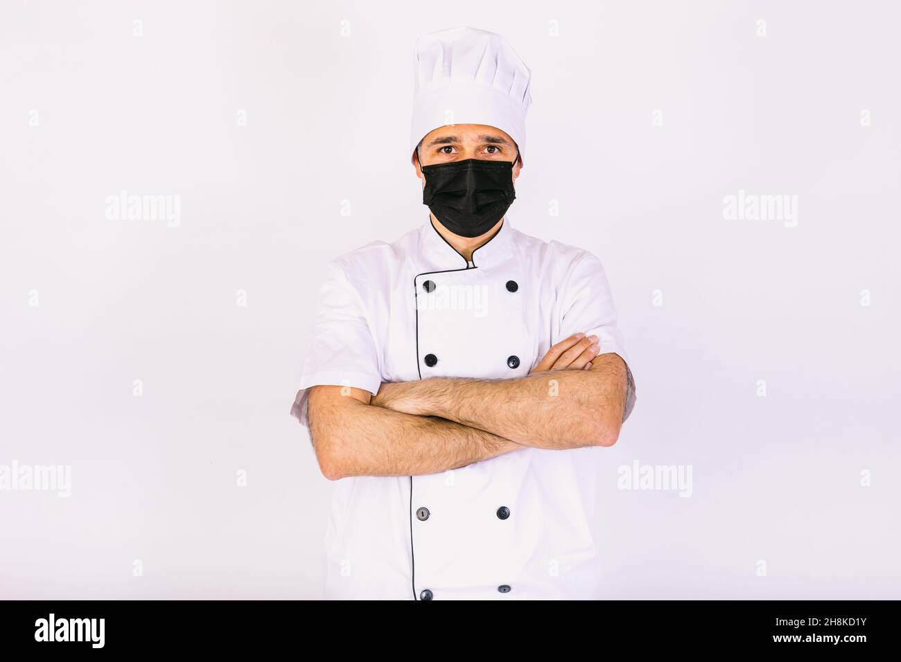 Chef cook wearing kitchen jacket and hat, with black mask, crossing ...