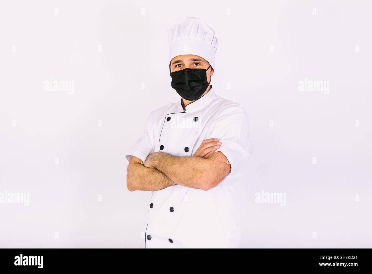 Chef cook wearing kitchen jacket and hat, with black mask, crossing ...
