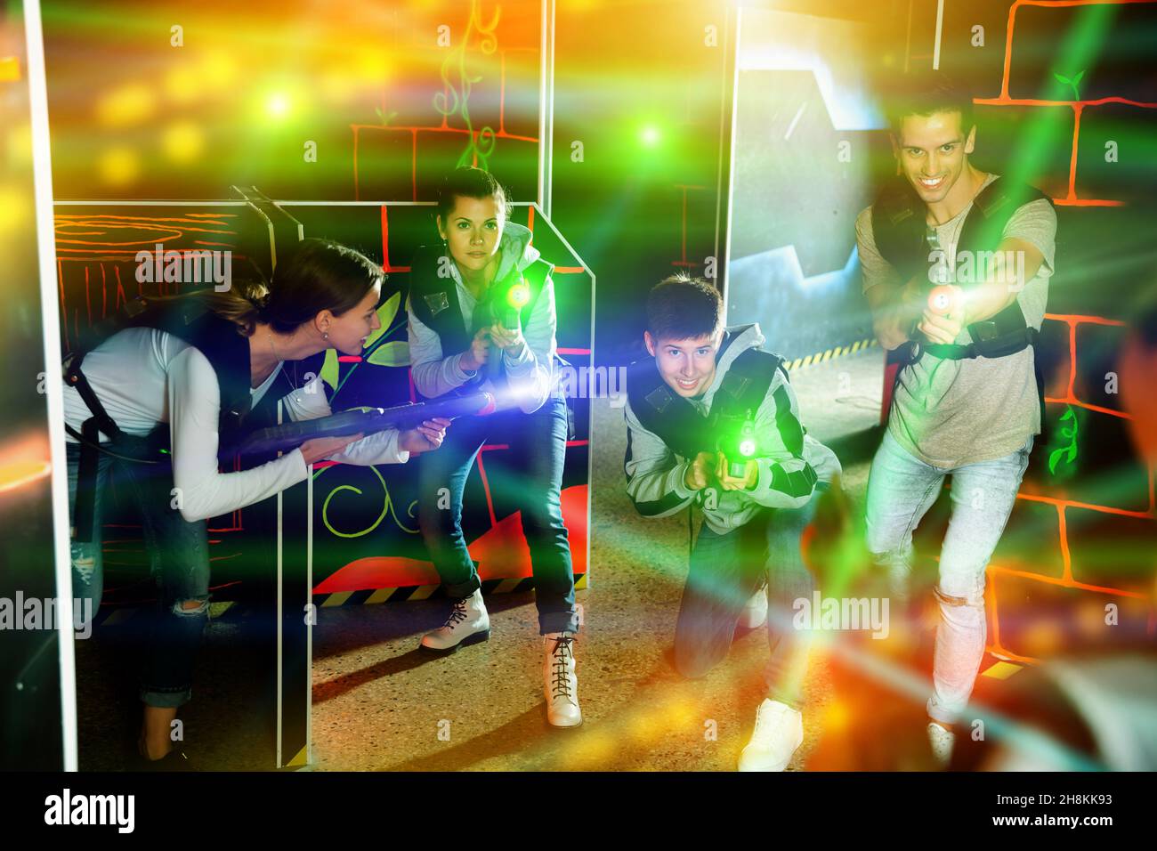 Modern young people with laser pistols playing laser tag on dark Stock ...