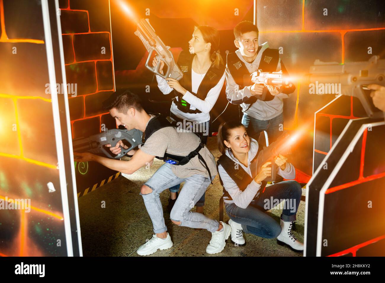 Modern young people with laser pistols playing laser tag on dark Stock ...