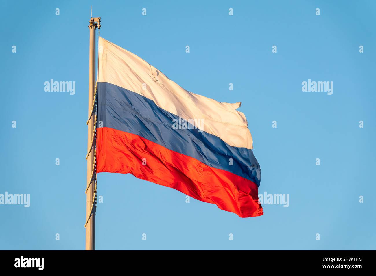 Russian tricolor flag waving in the wind against a blue sky. Russian ...