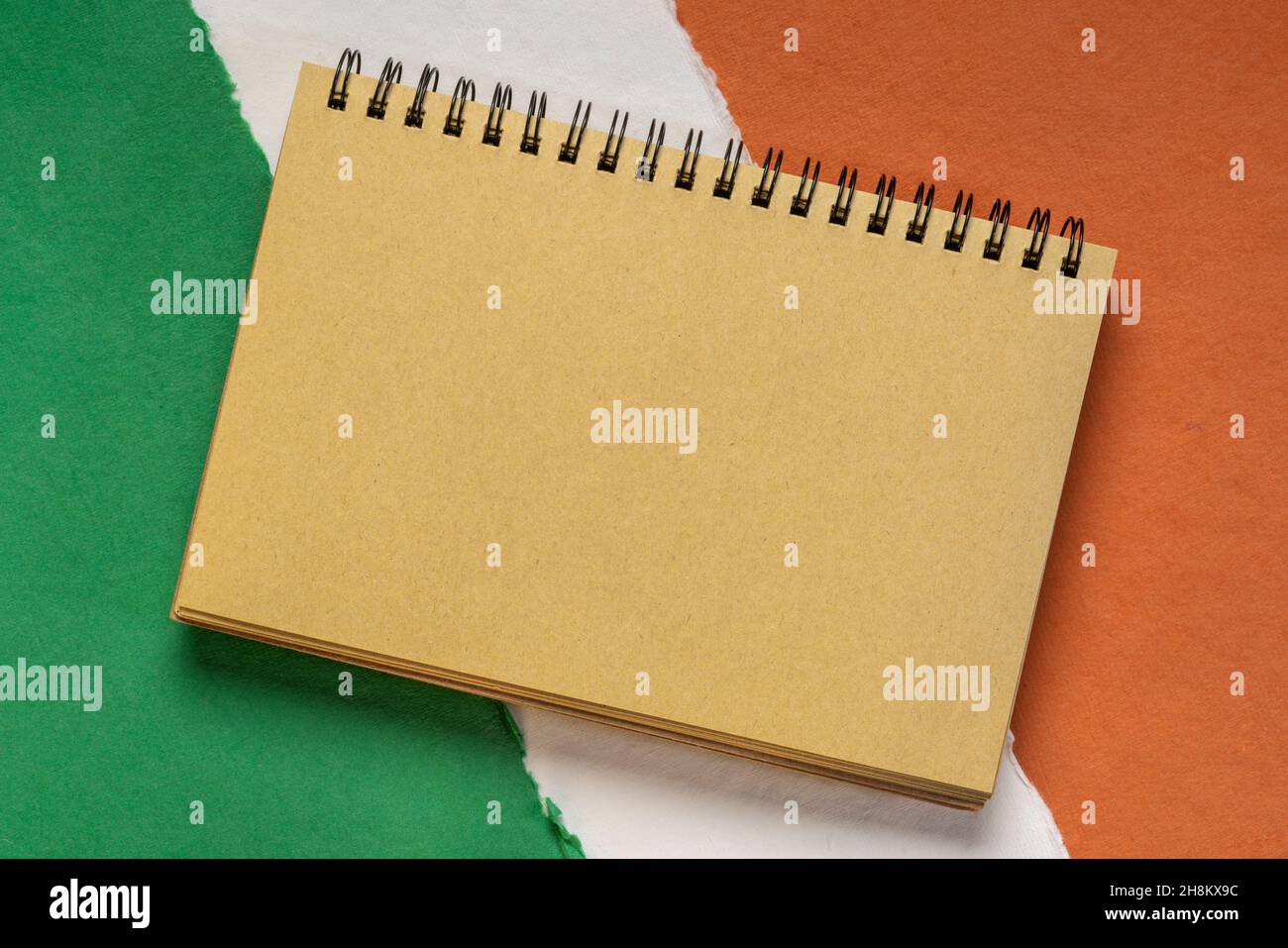 blank notebook against paper abstract in colors of national flag of ...