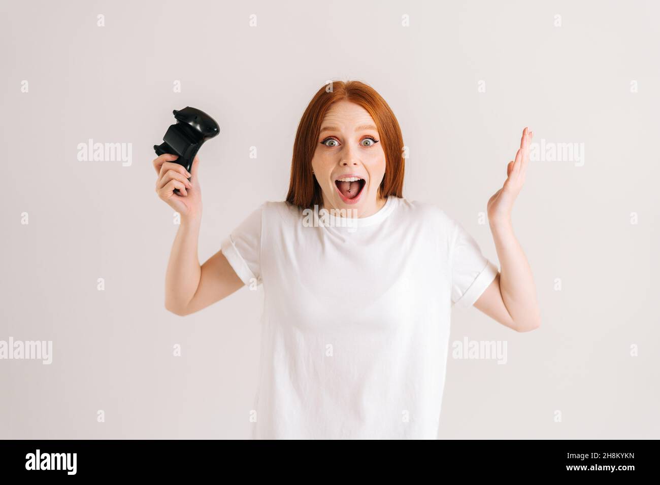 Studio portrait of cheerful young woman open mouth winning at video ...