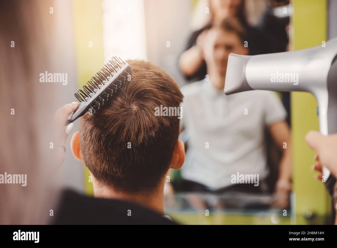 Master woman barber does hairstyle and styling with dryer hair to guy ...