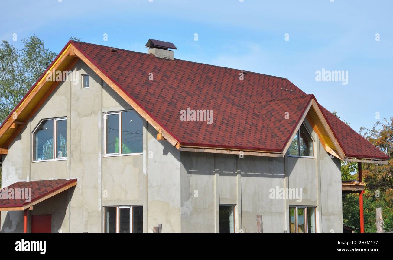 A house under construction with a red asphalt shingled roof, a chimney ...