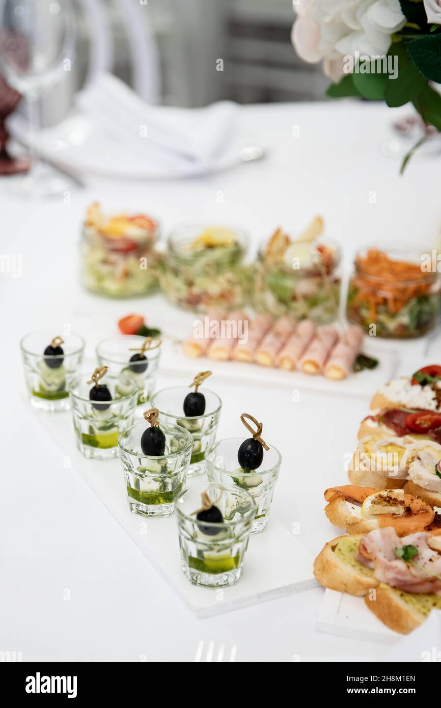 Wedding catering table in powdery pink color. Different food appetizers ...