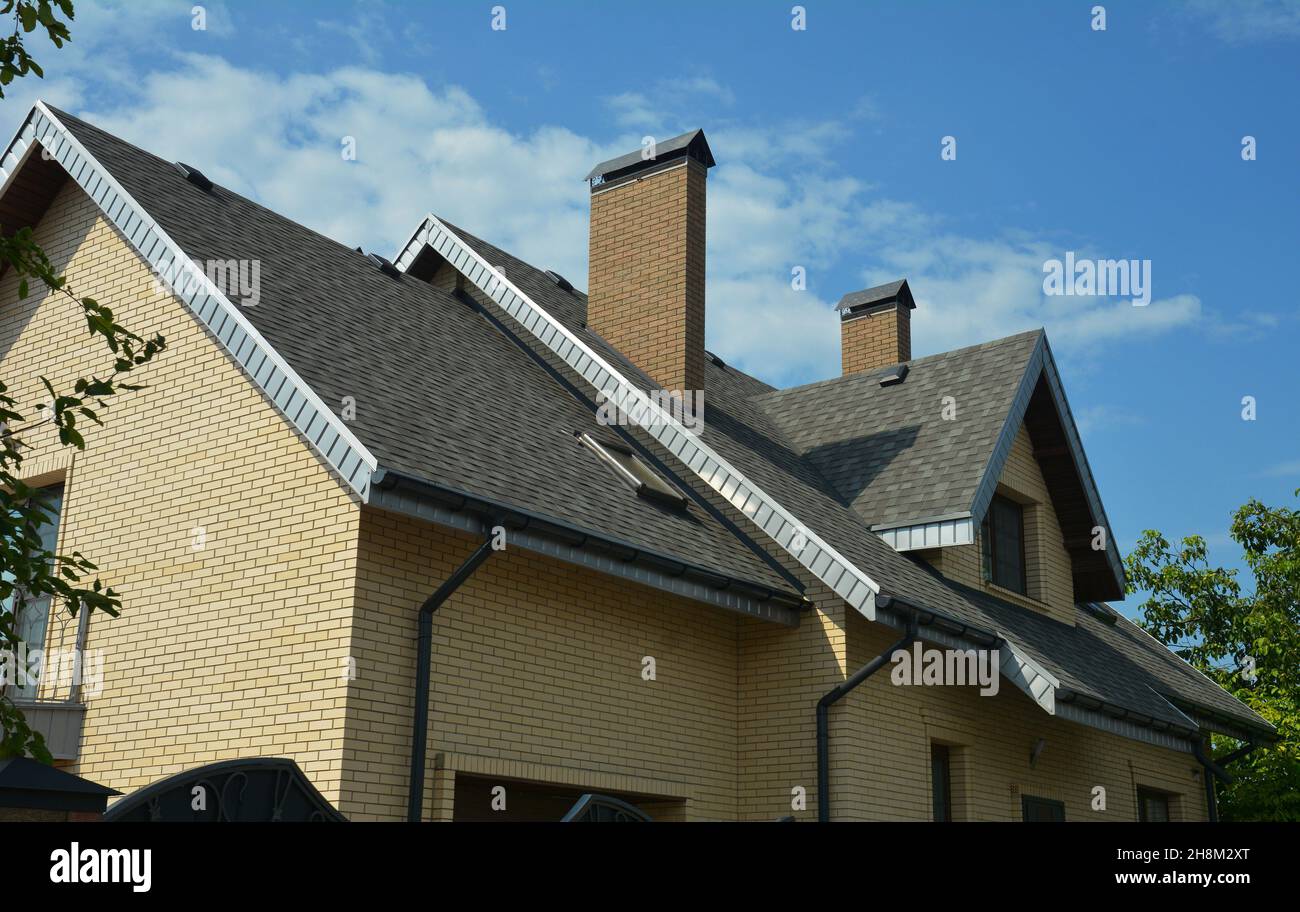 An asphalt shingled roof with skylights, attic windows, chimneys ...