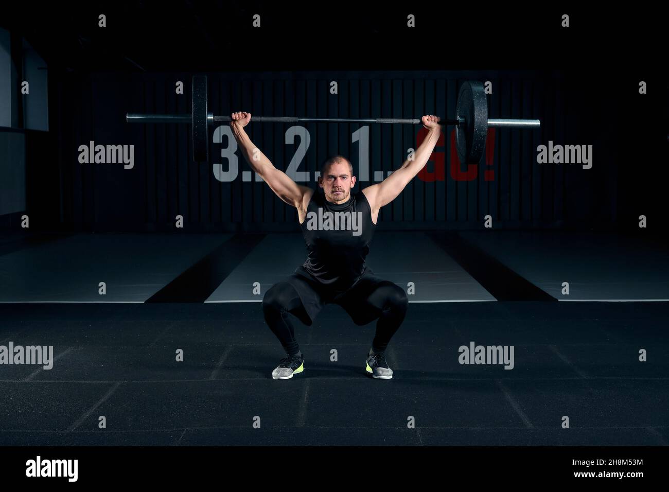 Sporty male doing workouts with barbell in a gym club Stock Photo - Alamy