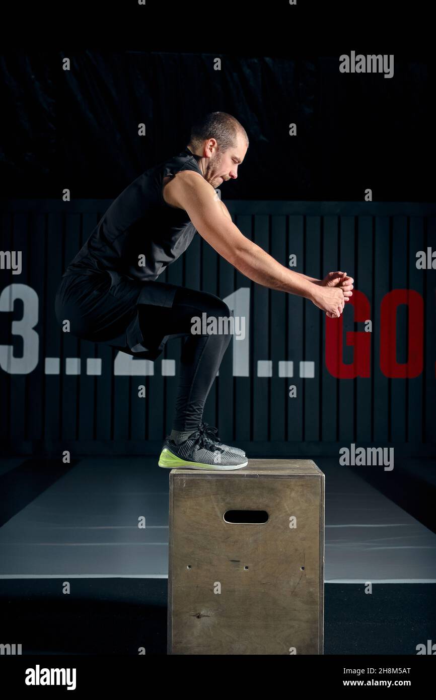 Fit young man jumping onto a box as part of exercise routine. Man doing ...
