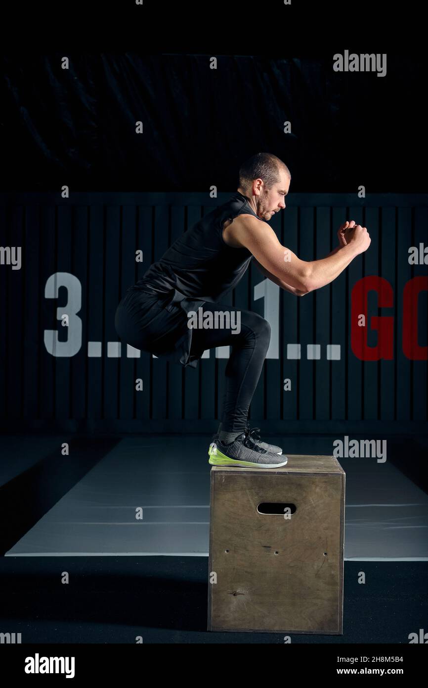 Fit young man jumping onto a box as part of exercise routine. Man doing ...