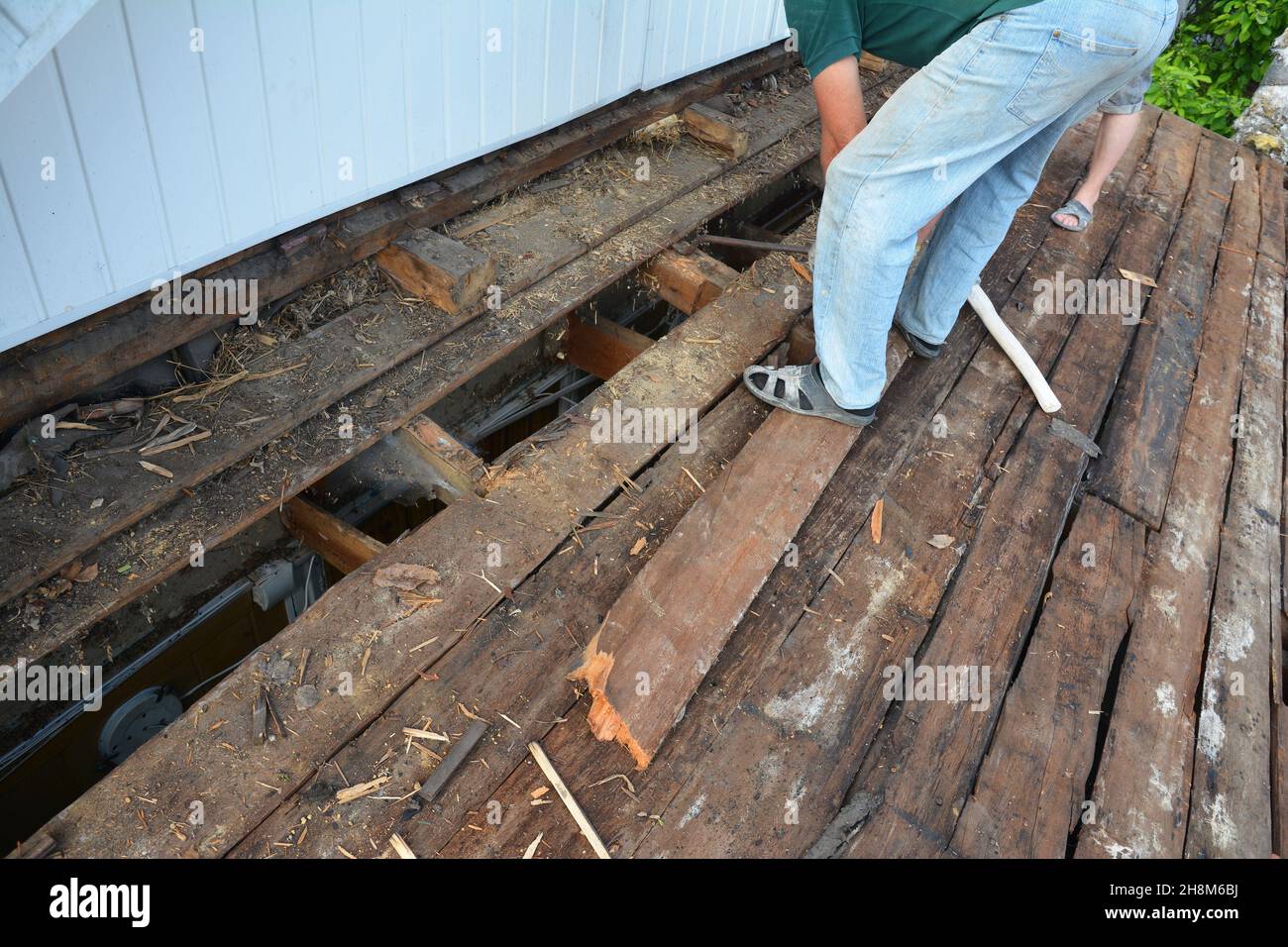 Old roof renovation, roof repair, and remodeling. A man is removing old ...