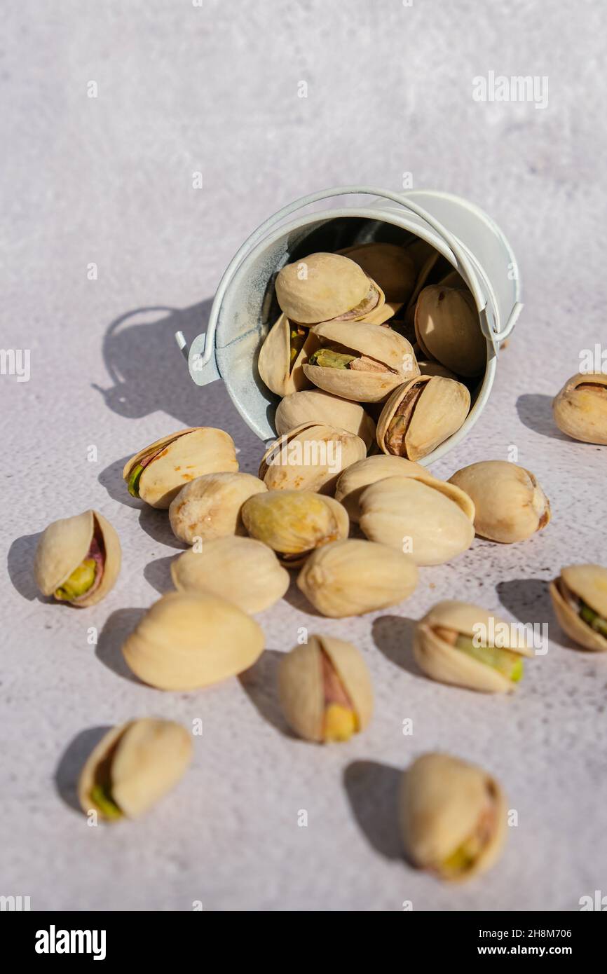 Pistachios in white bucket on concrete background. Healthy and dietary ...