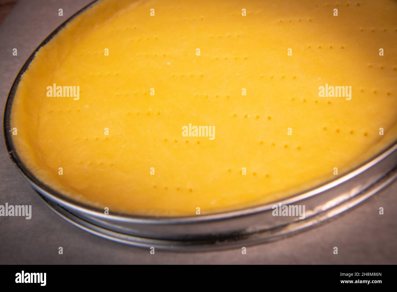 Metal fork makes holes in a raw pastry case in a metal baking tin Stock ...