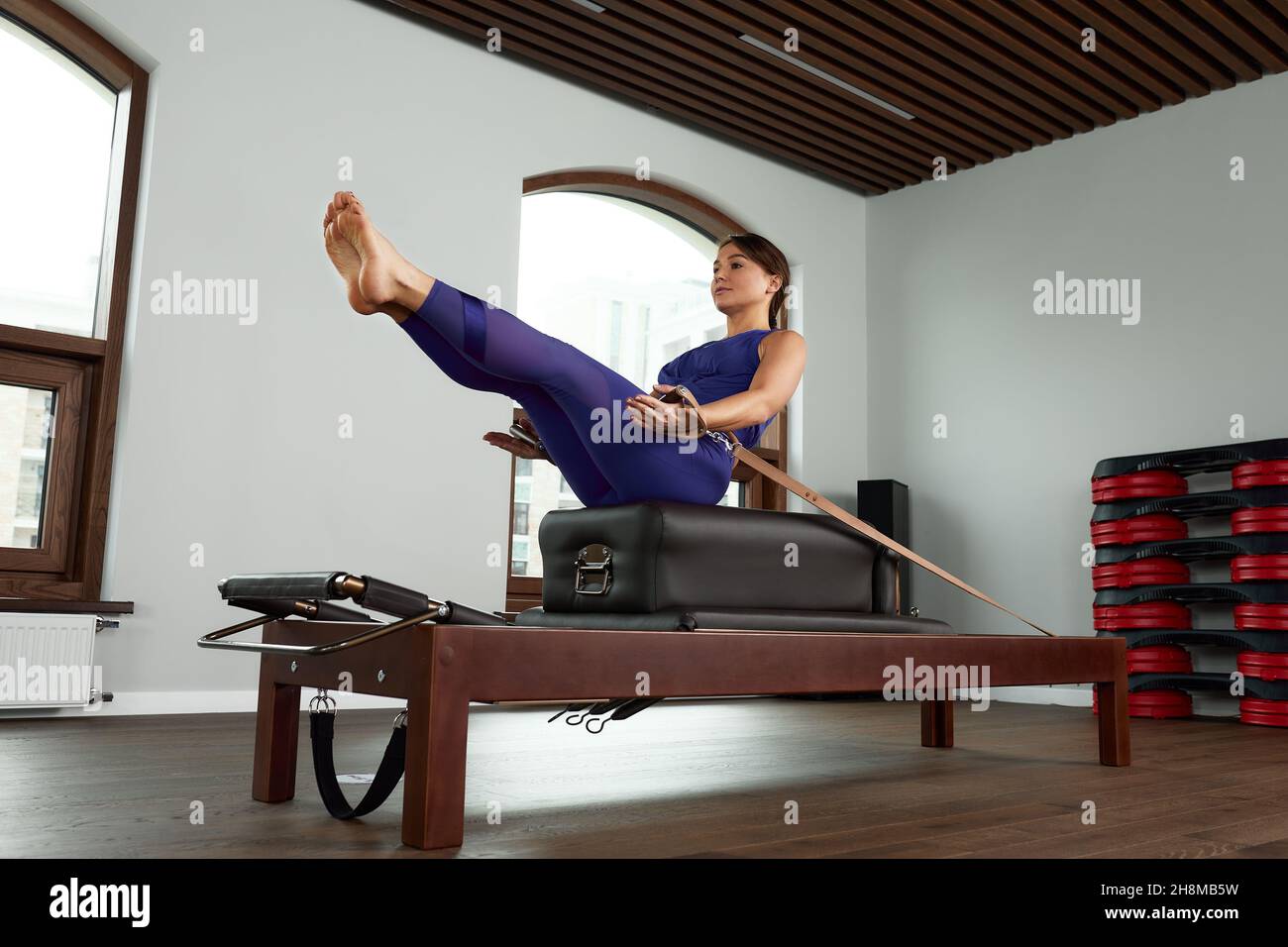 The instructor does exercises on the reformer, a beautiful girl trains ...