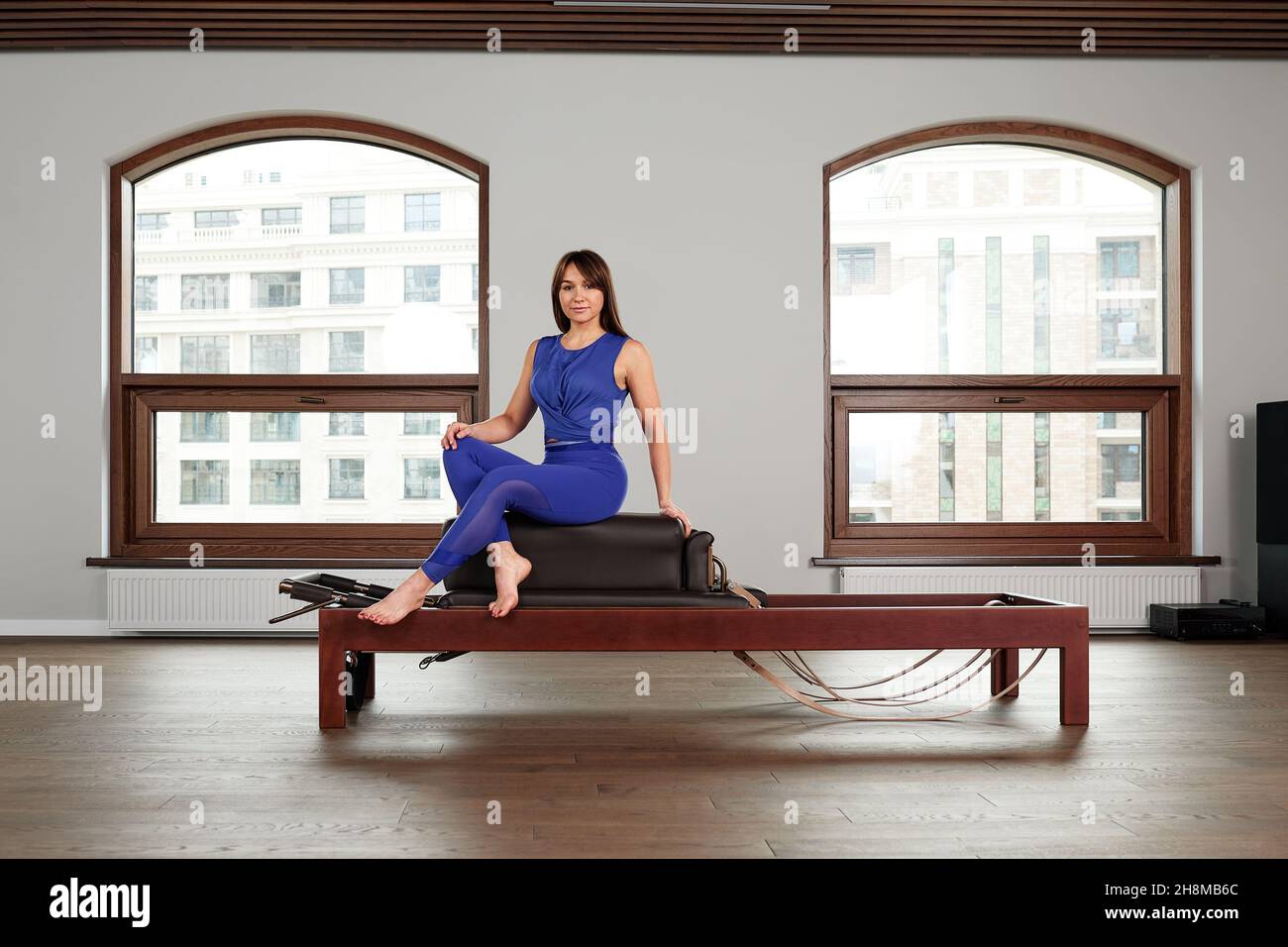 The instructor does exercises on the reformer, a beautiful girl trains ...