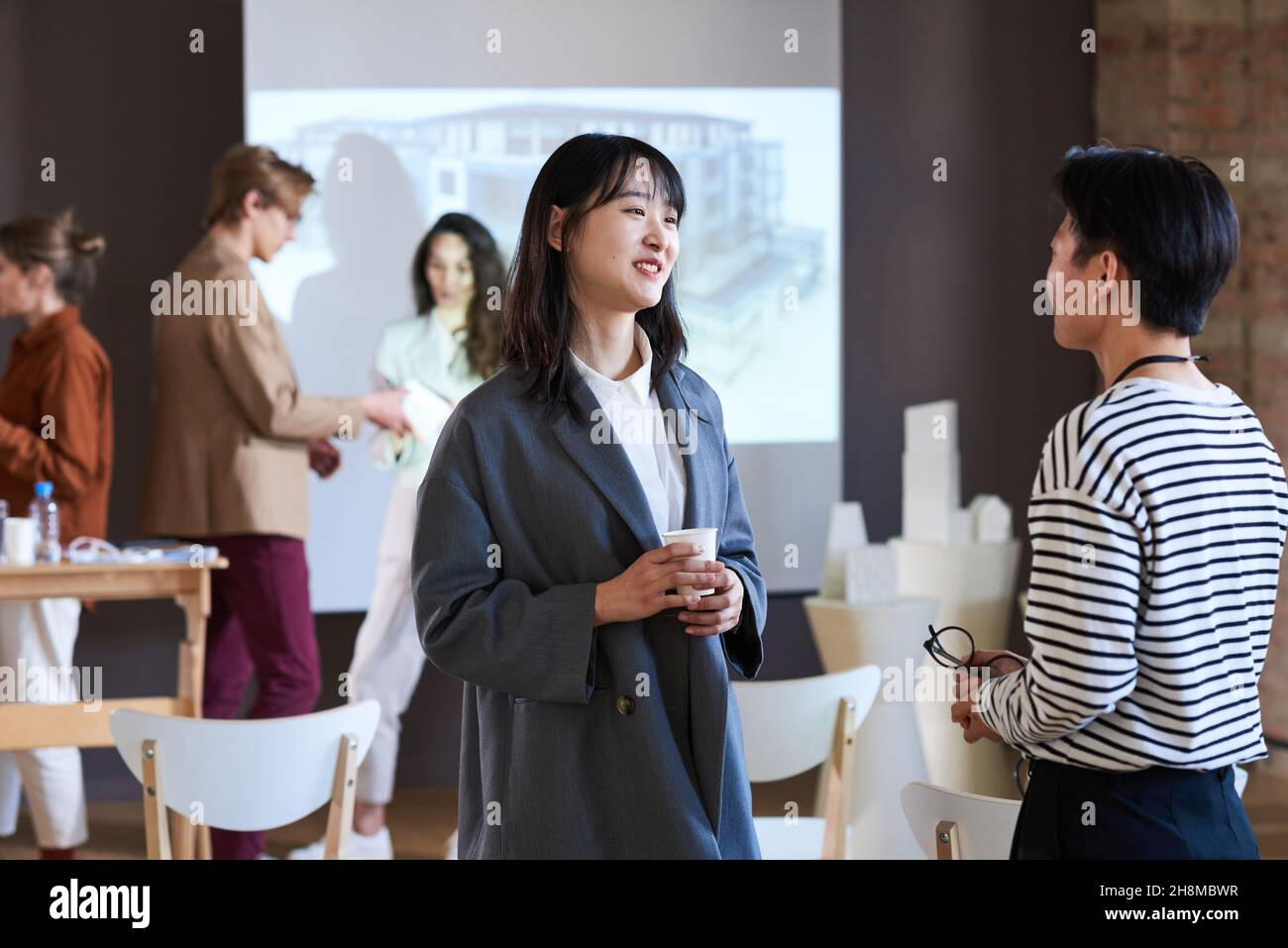 Asian young businesswoman talking to her colleague while they visiting ...