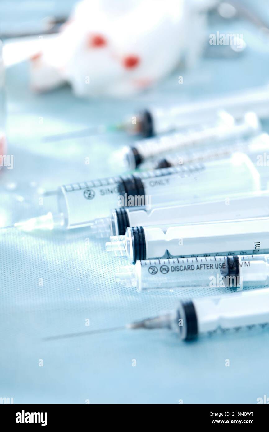 Many syringes on a blue sheet in operation room. Different sizes of ...