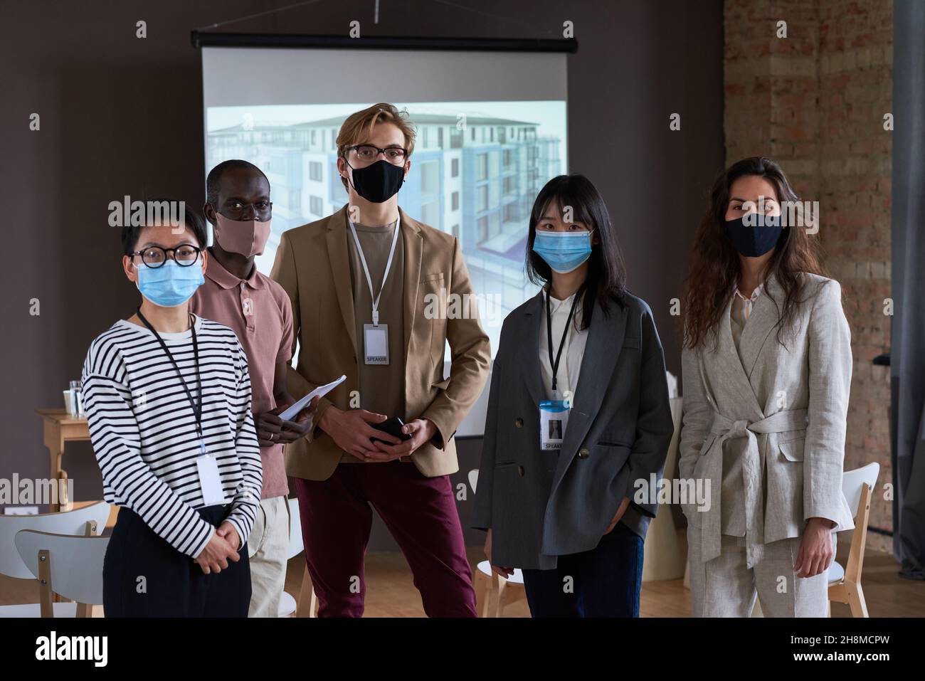 Portrait of group of business people in masks looking at camera while ...