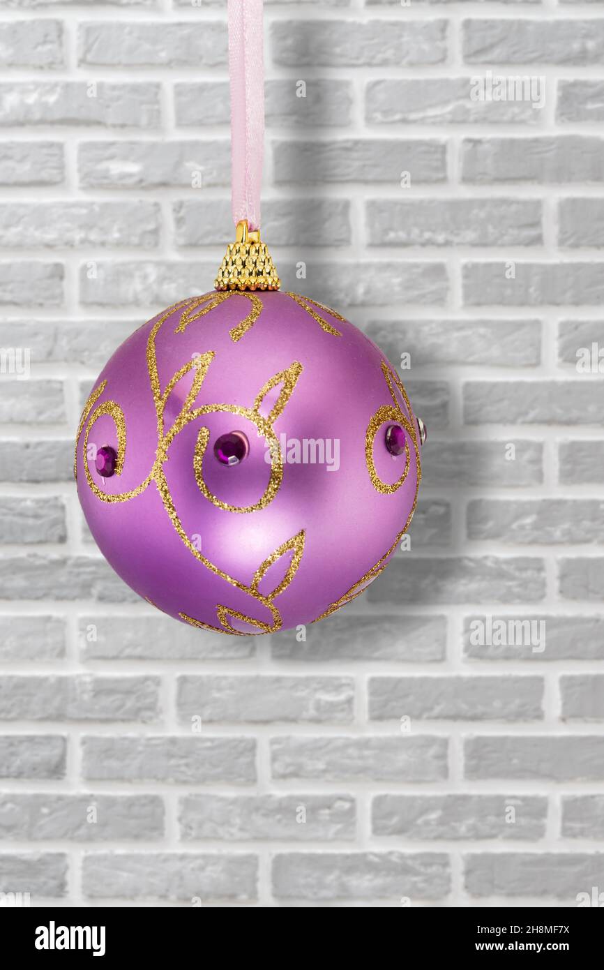 Lilac Christmas ball and a gray brick wall on the background. Christmas ...
