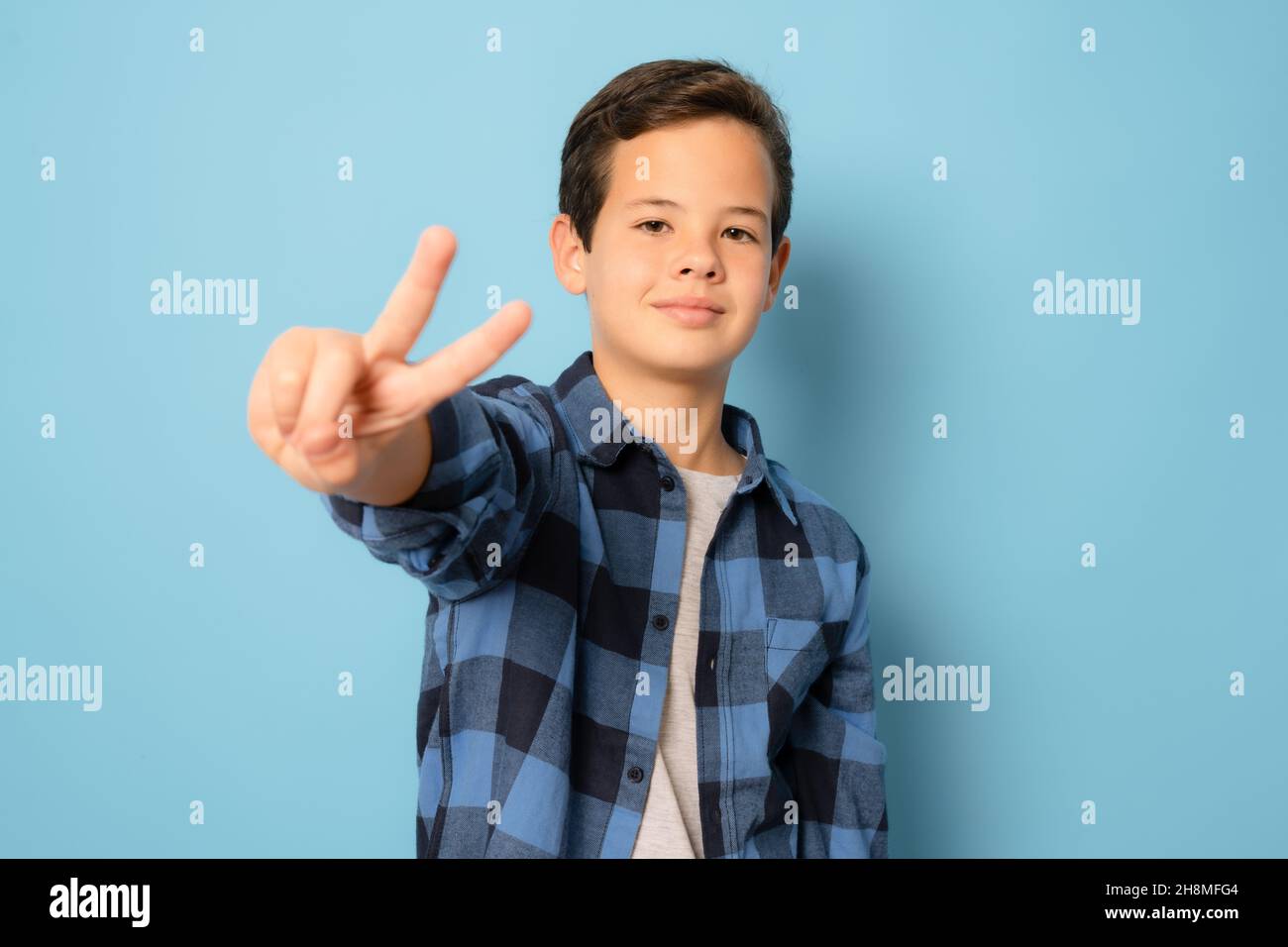 Cute kid boy in plaid shirt showing peace sign isolated over blue ...