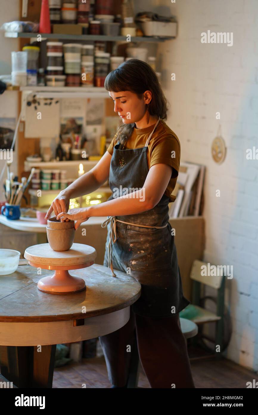 Ceramist in apron molding vase at master class in studio. Young woman ...