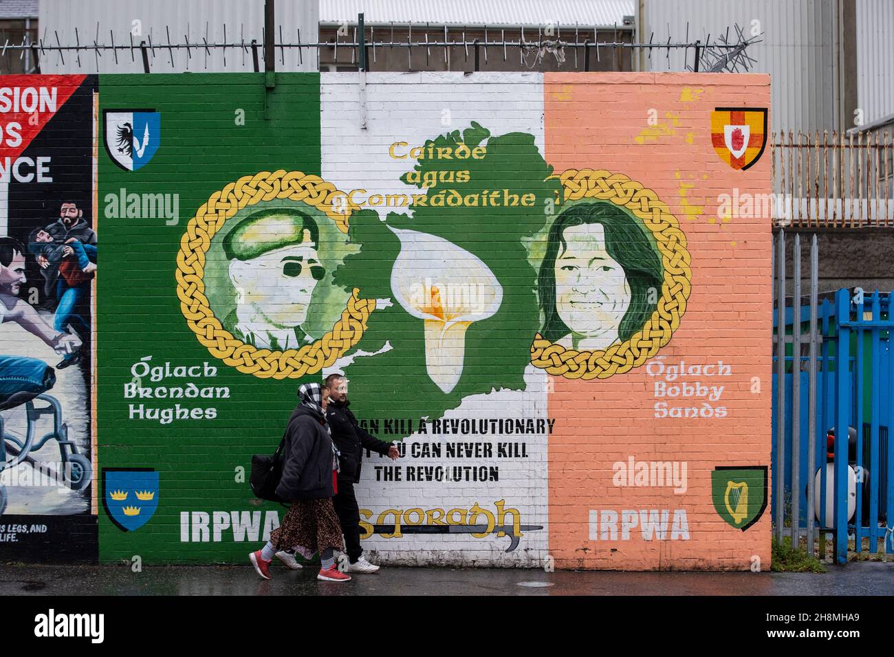 Two people walk past a Saoradh mural painted on International Wall in ...