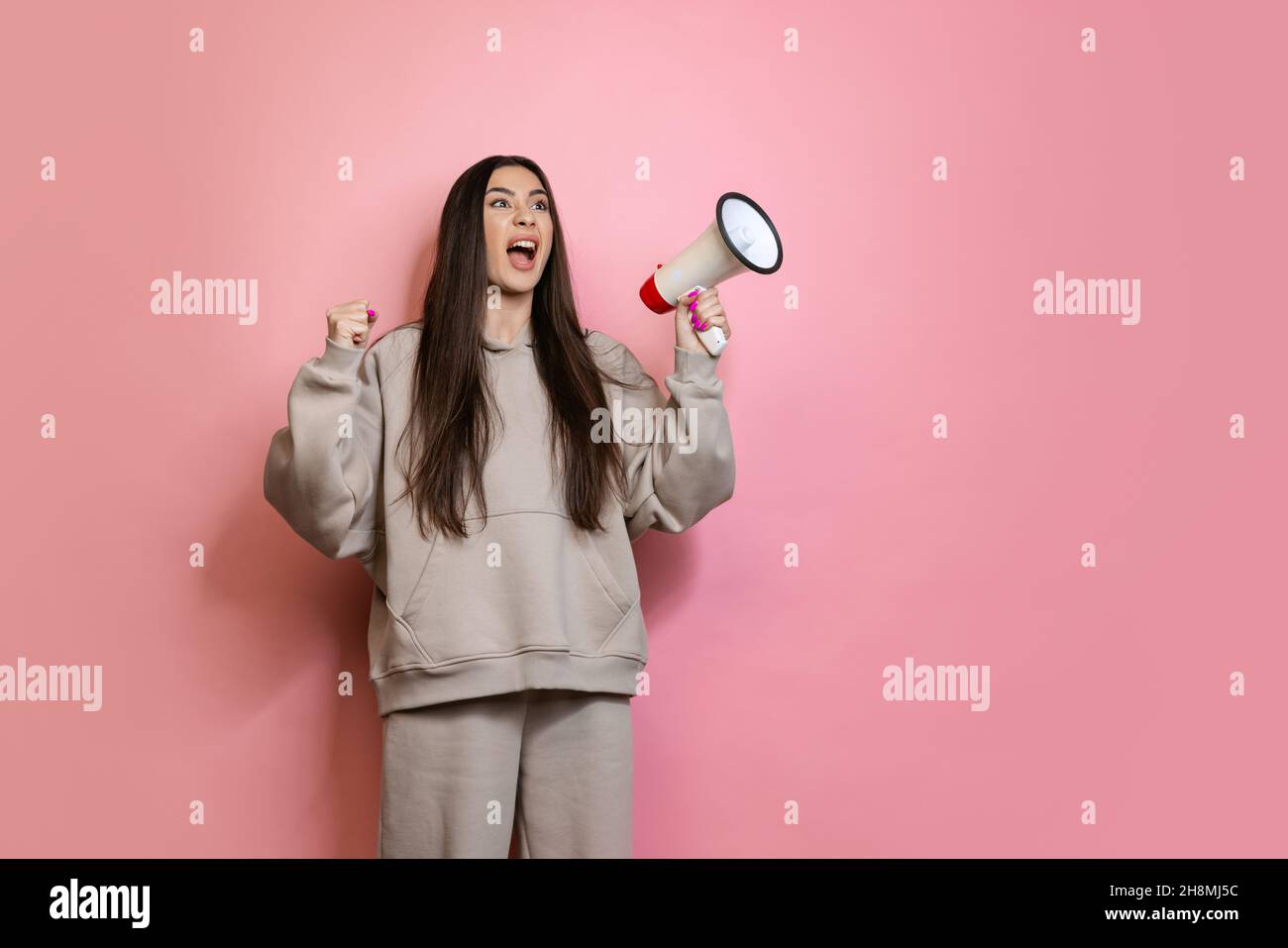 Cropped portrait of young excited girl shouting into megaphone isolated ...