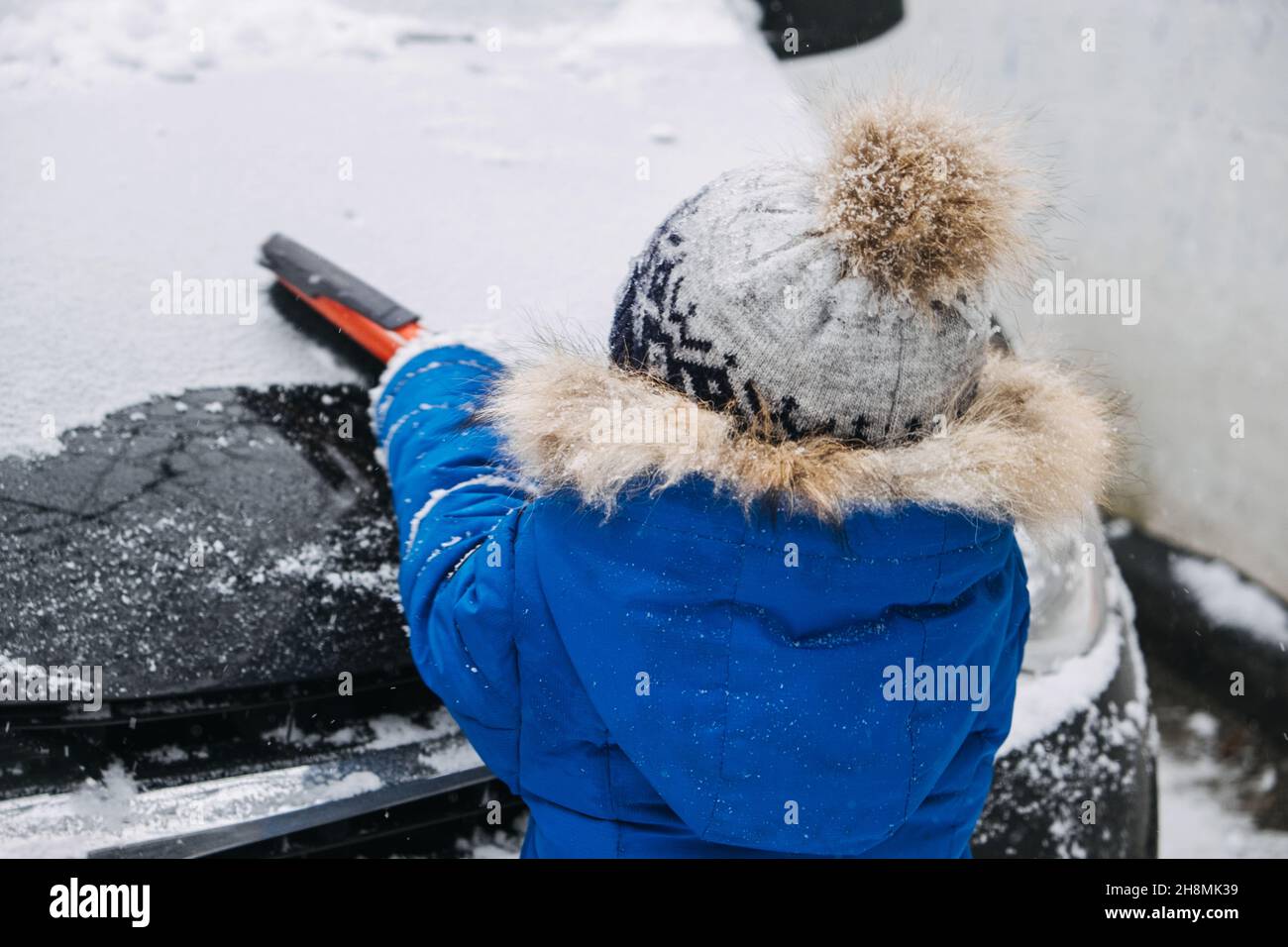 Cute little boy cleaning snow off the car at winter backyard. Little ...