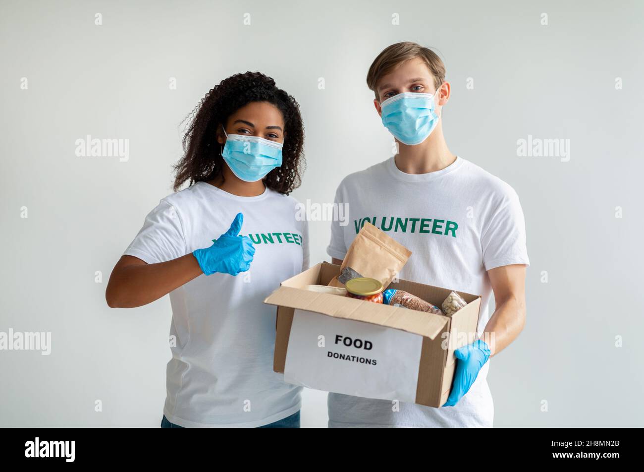 Charity center. Millennial diverse volunteers in face masks holding ...
