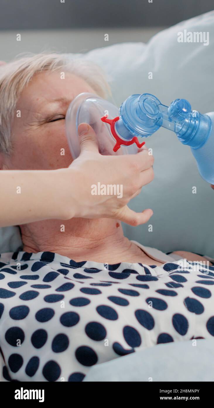 Close up of hyperventilating woman in hospital ward bed while doctor ...