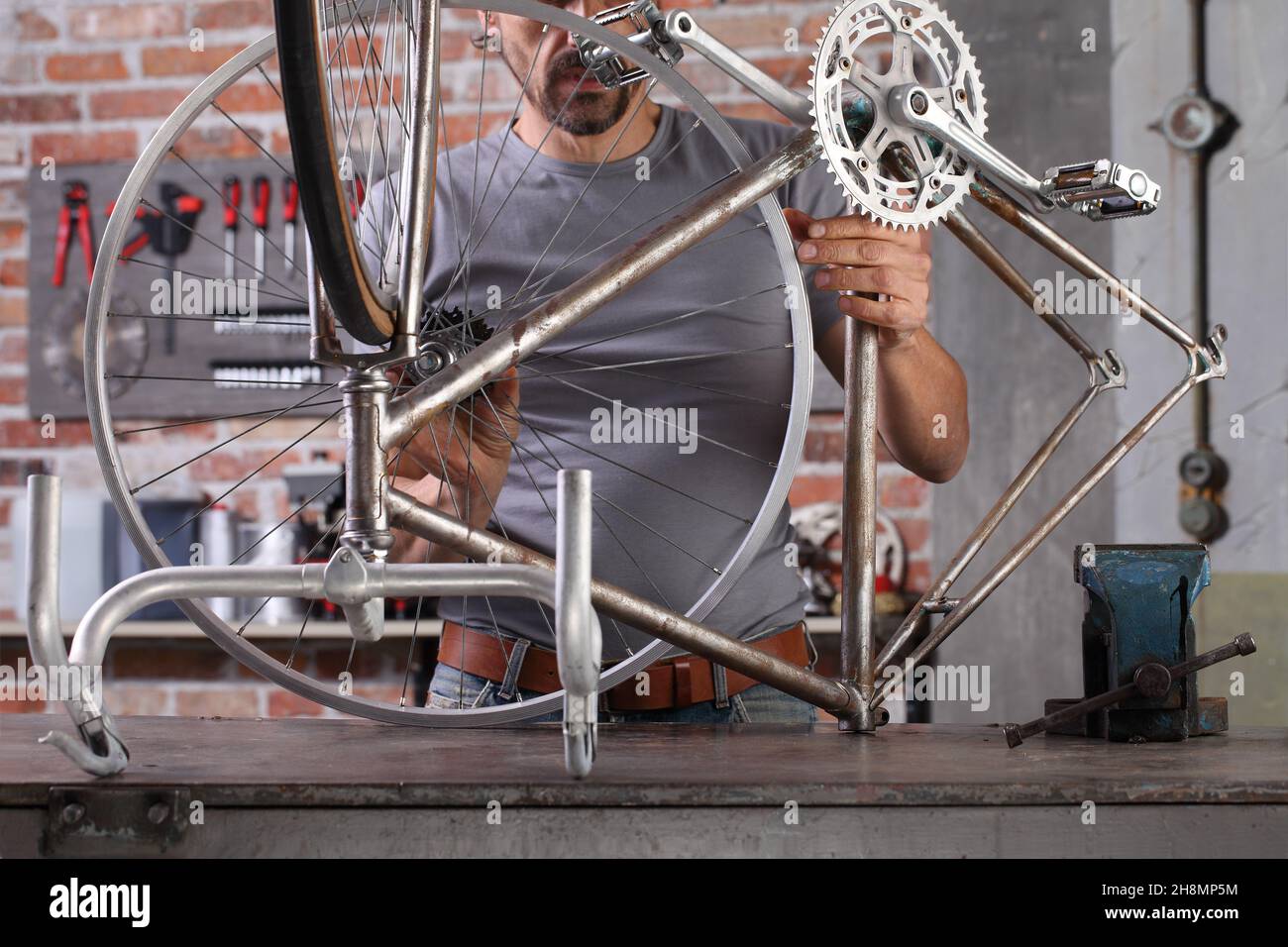 man repair the vintage bicycle in garage workshop on the workbench with ...