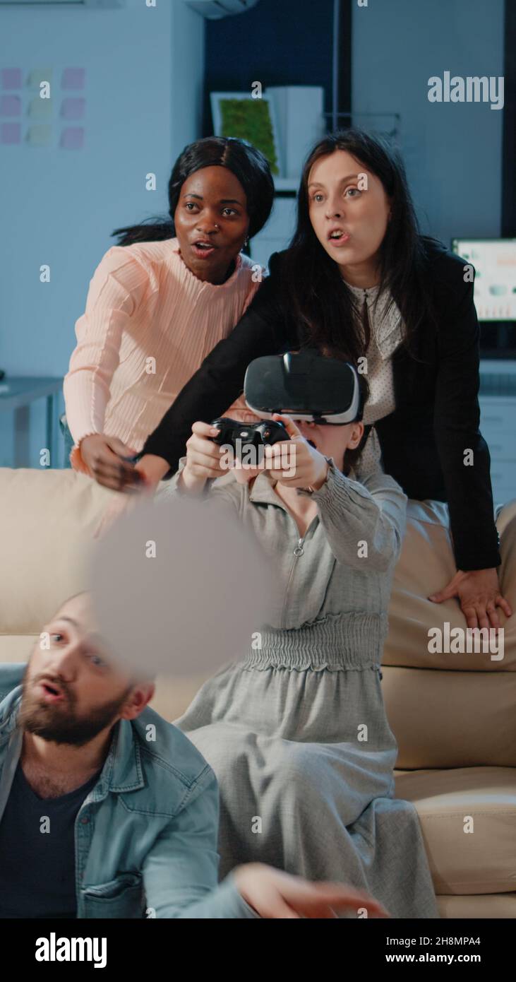 Cheerful colleagues having fun with video games after work, using vr ...