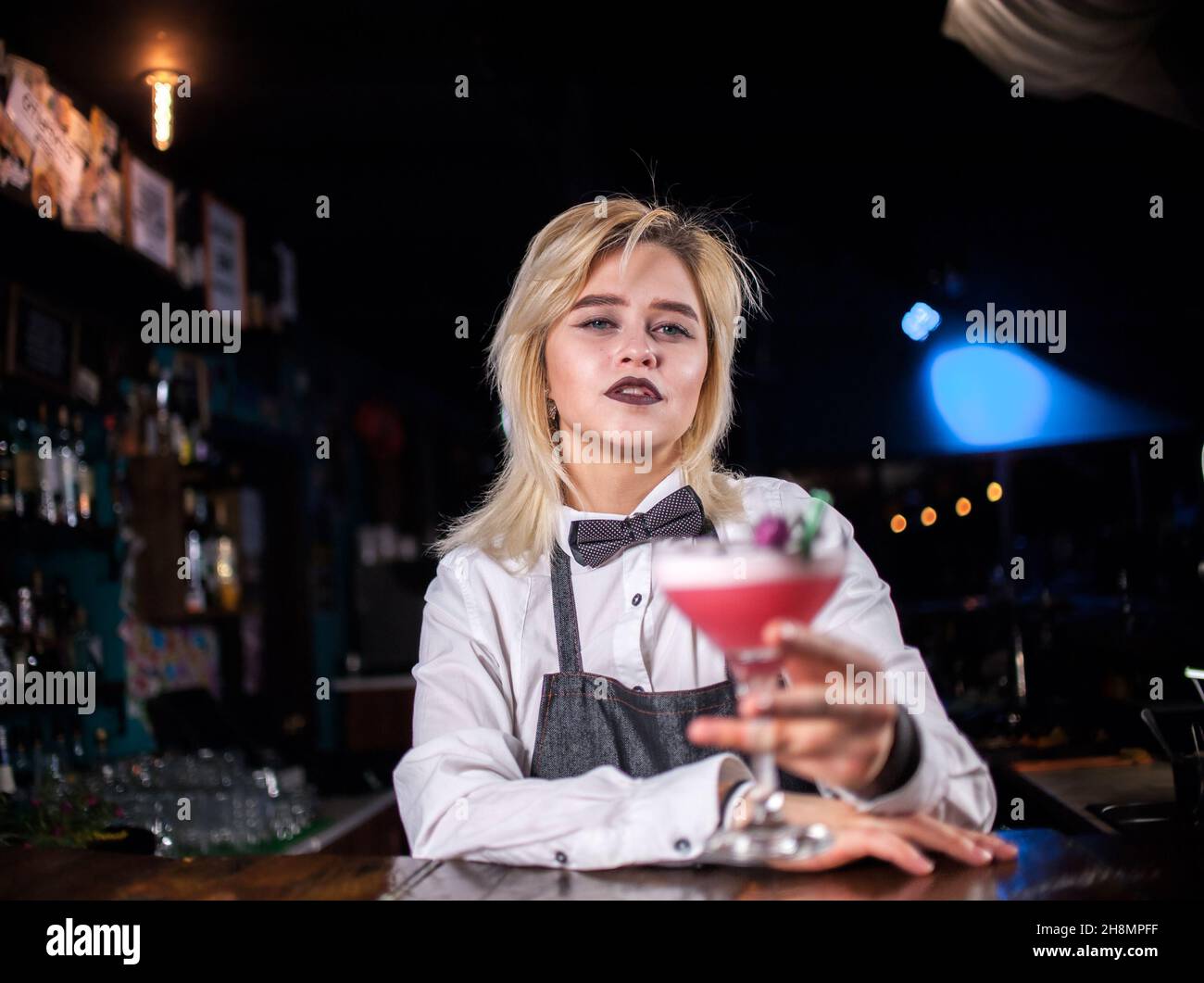 Young girl bartender demonstrates the process of making a cocktail ...