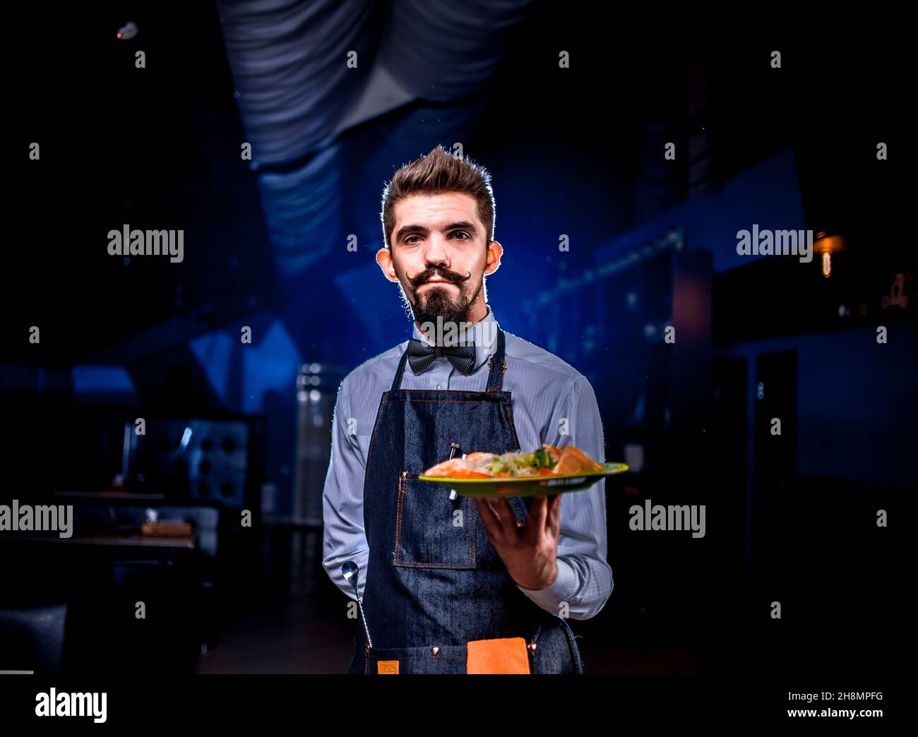 Professional waiter helpfully serves salad on a black background Stock ...