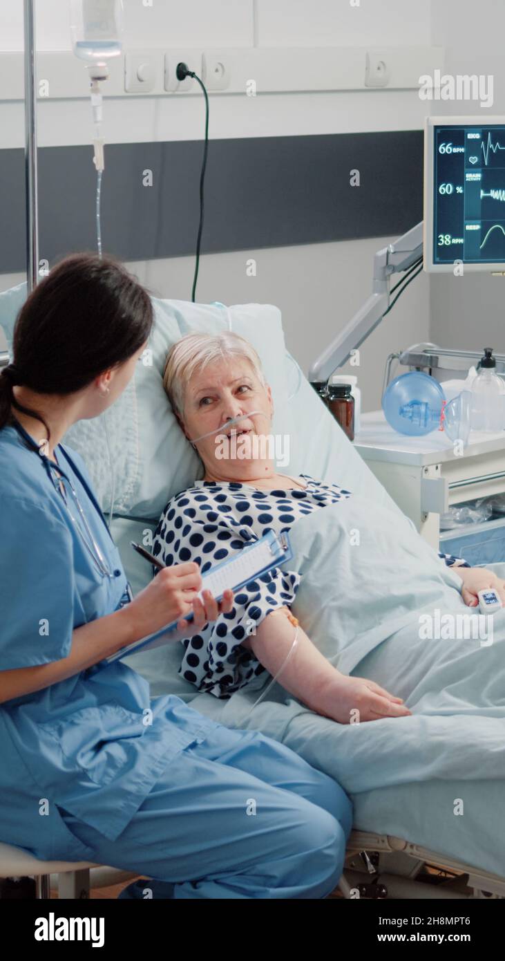 Nurse giving assistance to senior patient with disease in bed. Medical ...