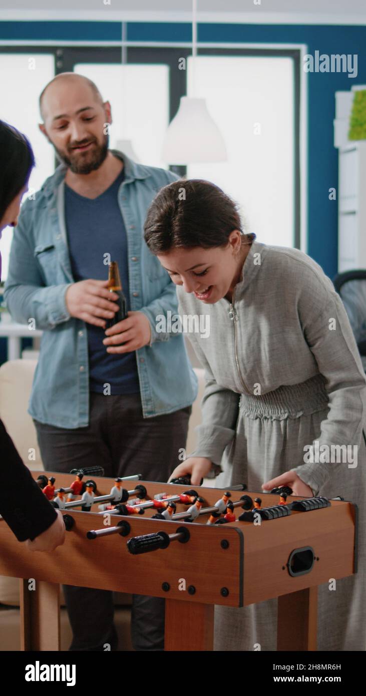 Cheerful women playing at foosball game table after work. Workmates ...