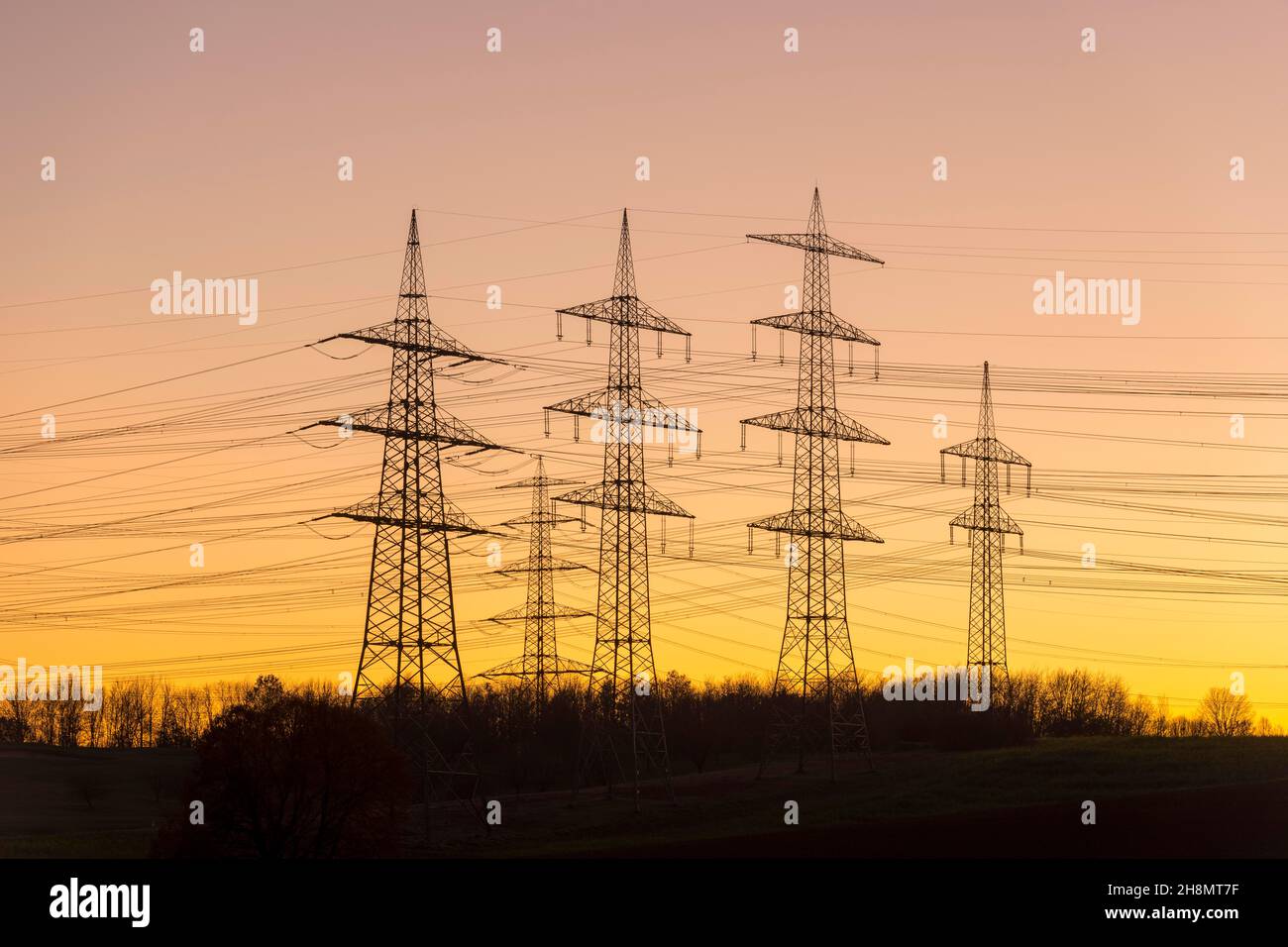 High-voltage pylons, electricity pylons in front of water vapour cloud ...