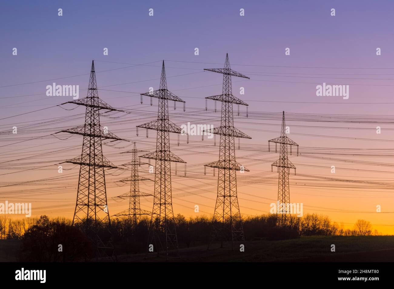 High-voltage pylons, electricity pylons in front of water vapour cloud ...