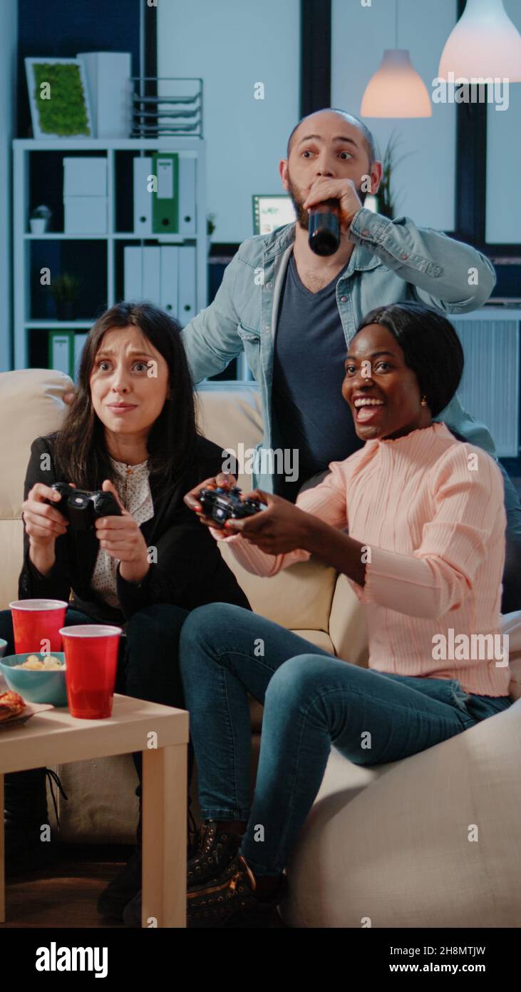 Cheerful coworkers playing video games with joysticks and console on ...