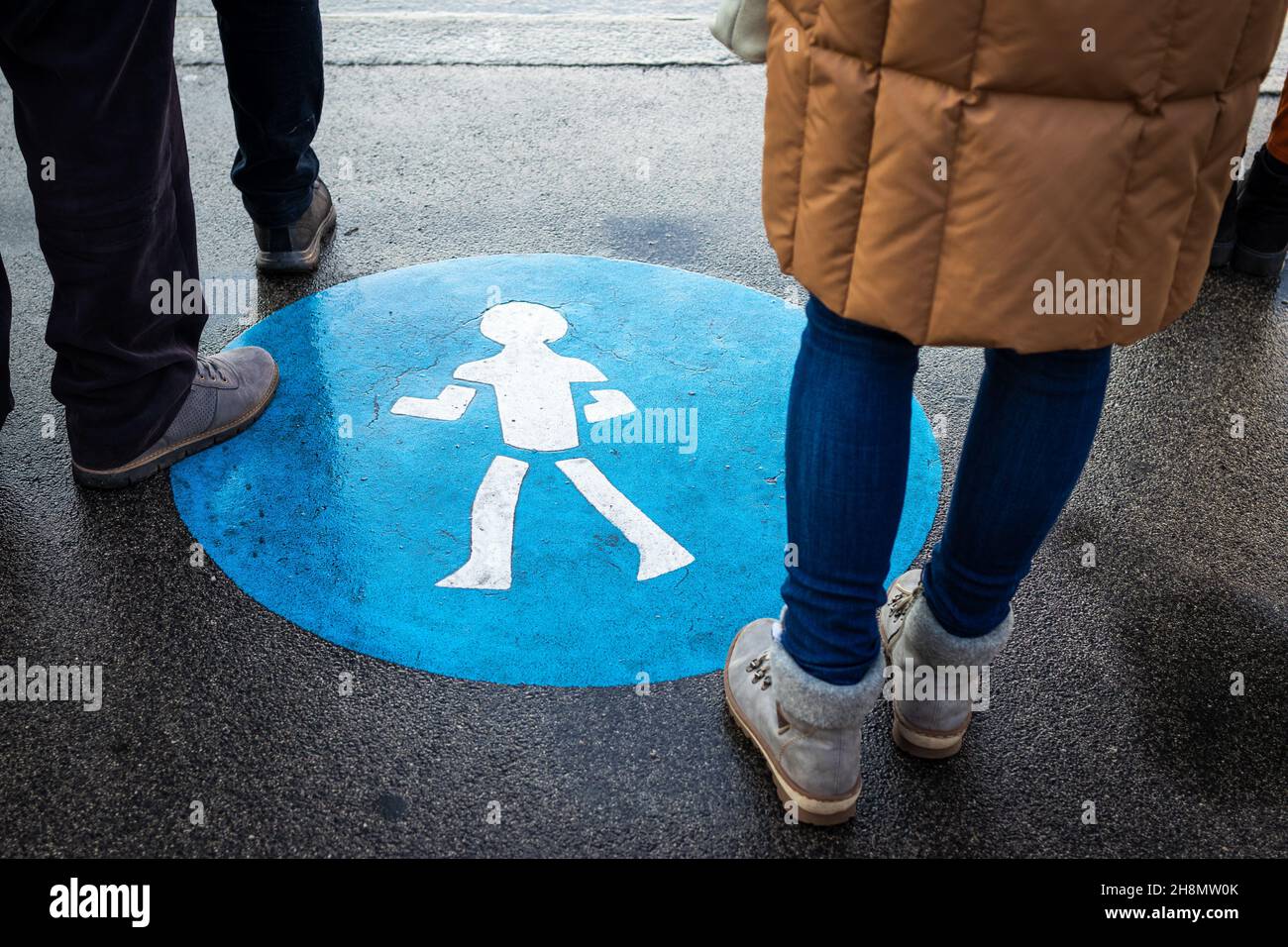 People waiting at pedestrian crosswalk in city street. Road sign on ...