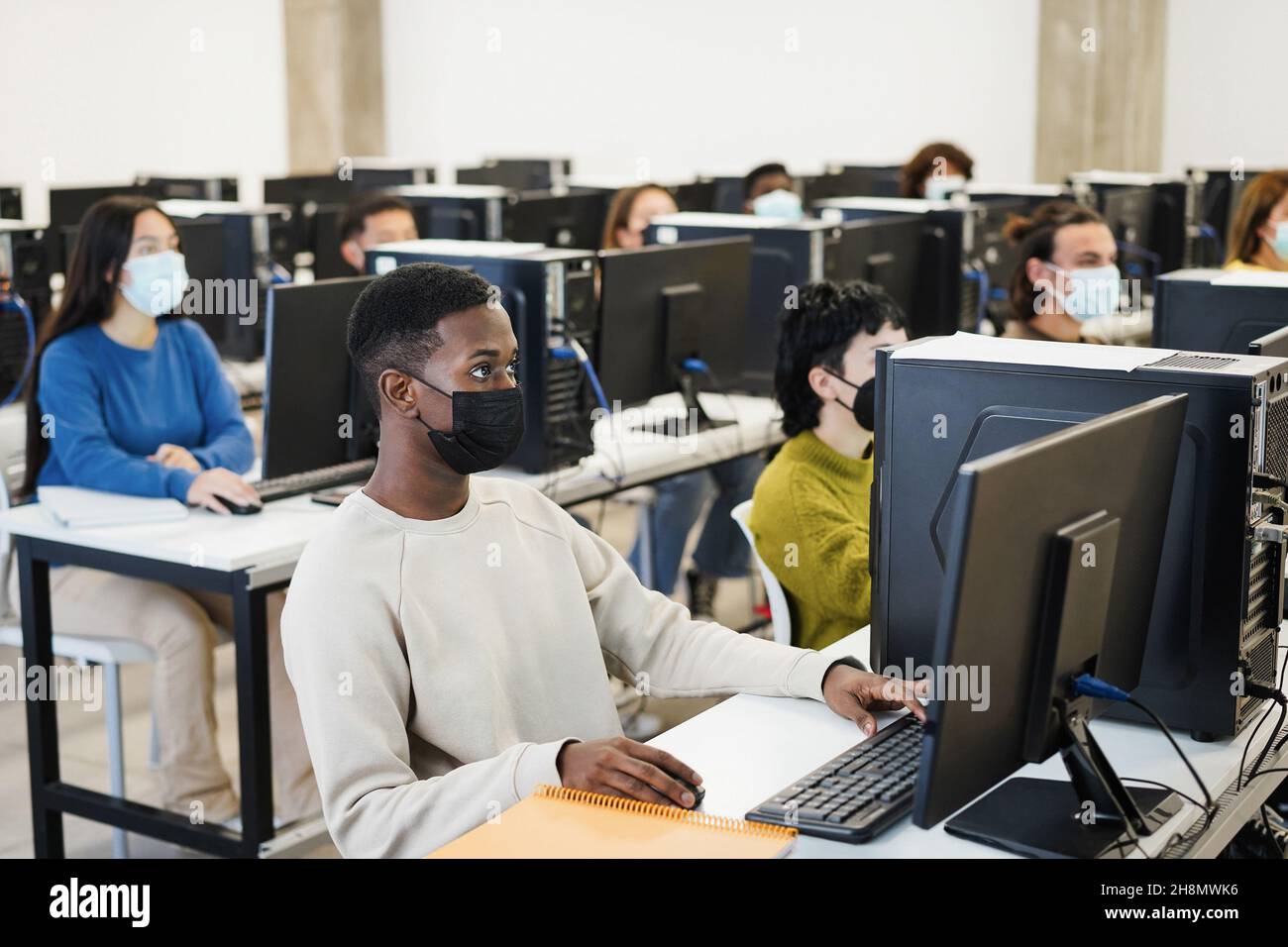 Multiracial young students using computers inside class room wearing ...