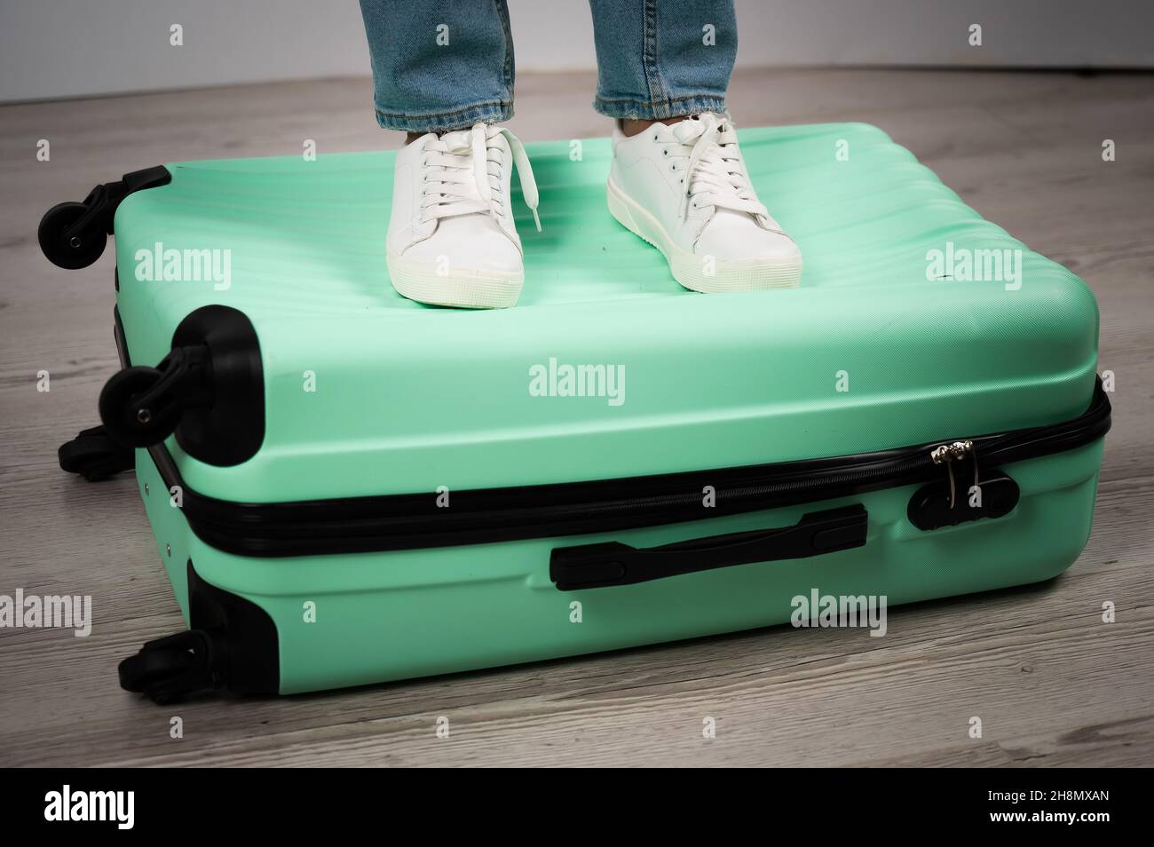Woman standing with her feet on a suitcase Stock Photo - Alamy