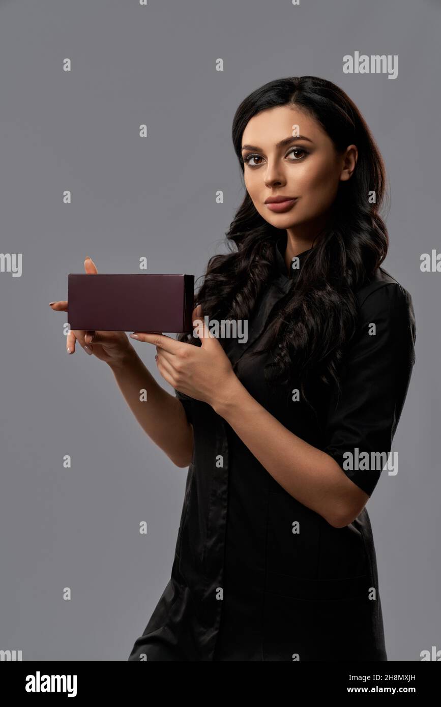 Female beauty doctor in black medical uniform and gloves holding boxes ...