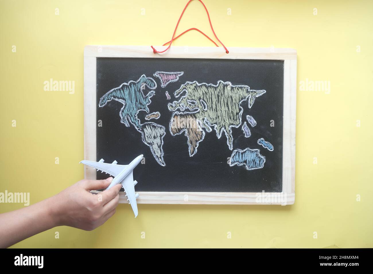 travel concept with hand hold a airplane on world map drown on chalk ...