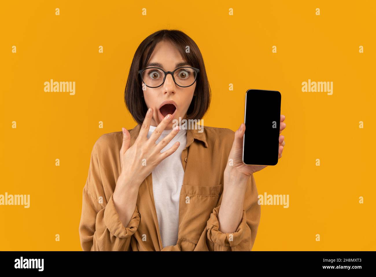 Emotional lady showing smartphone with blank screen and covering her ...