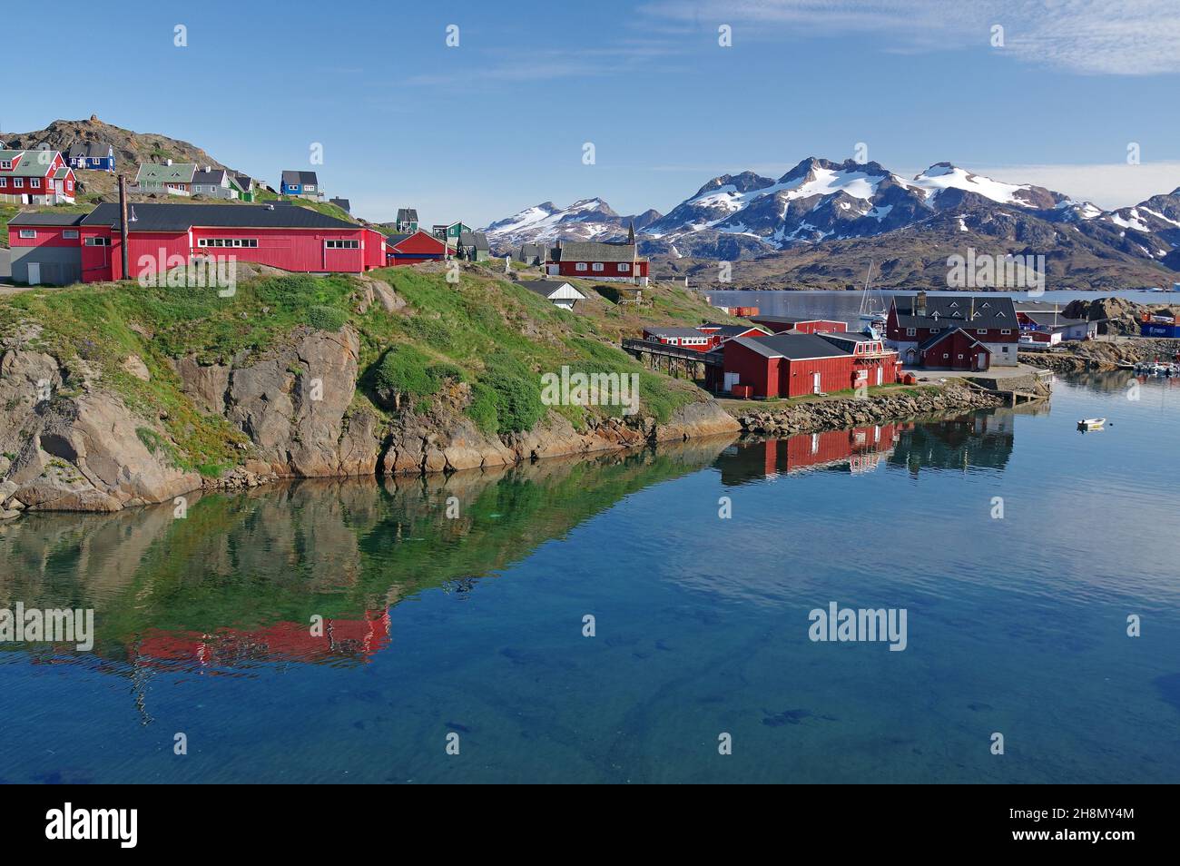 Houses on the shallow shore of a fjord, snow-capped mountains, Tasilaq ...