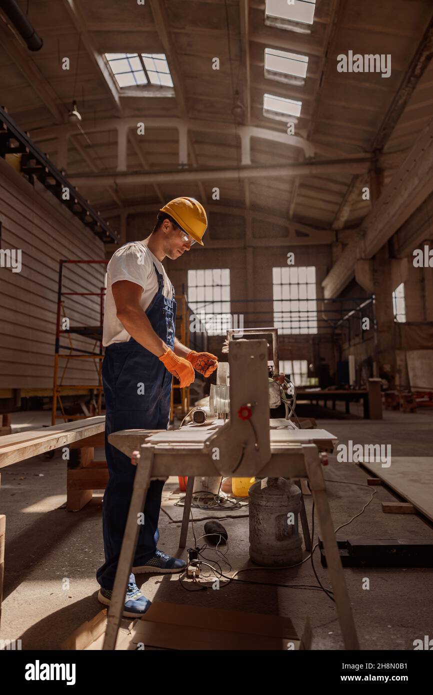 Handsome male worker using woodworking machine in workshop Stock Photo ...