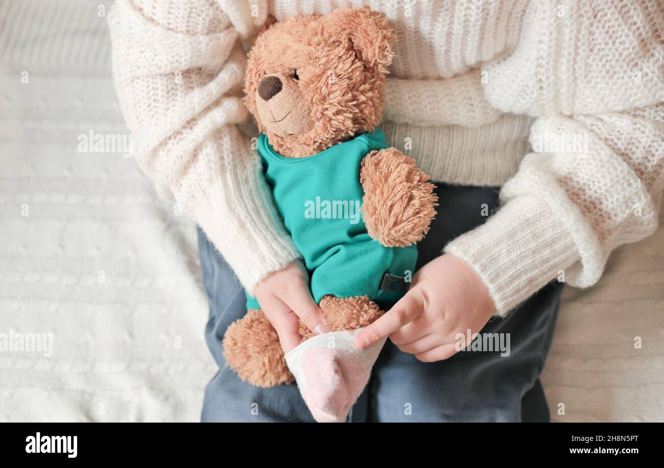 little girl gettng her teddy bear ready for a street walk. putting on ...