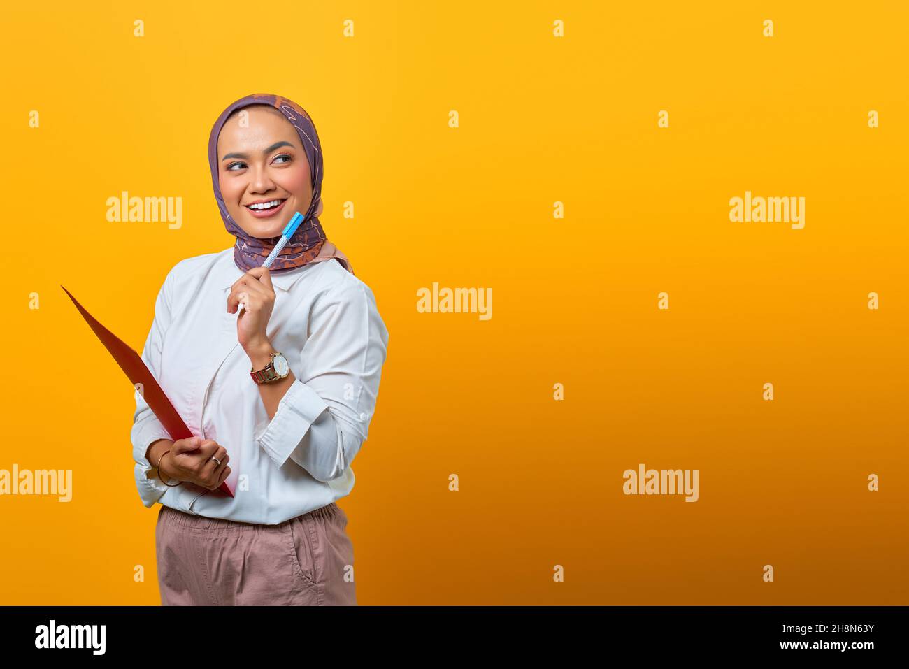 Beautiful Asian woman holding folders and pen looking at the side with ...
