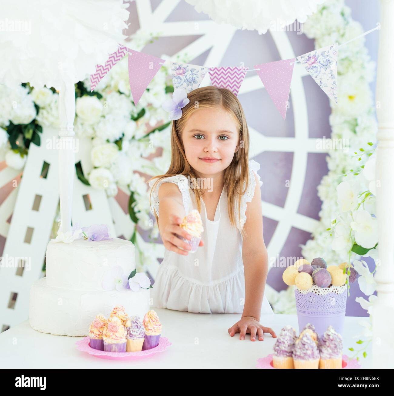 Pretty little blond girl standing in the beautiful decorated candy bar ...